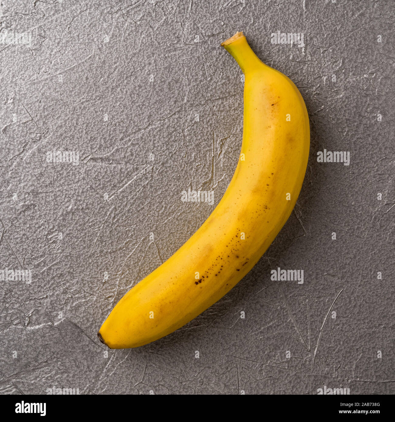 Simple image of single ripe yellow banana on gray metallic background ...