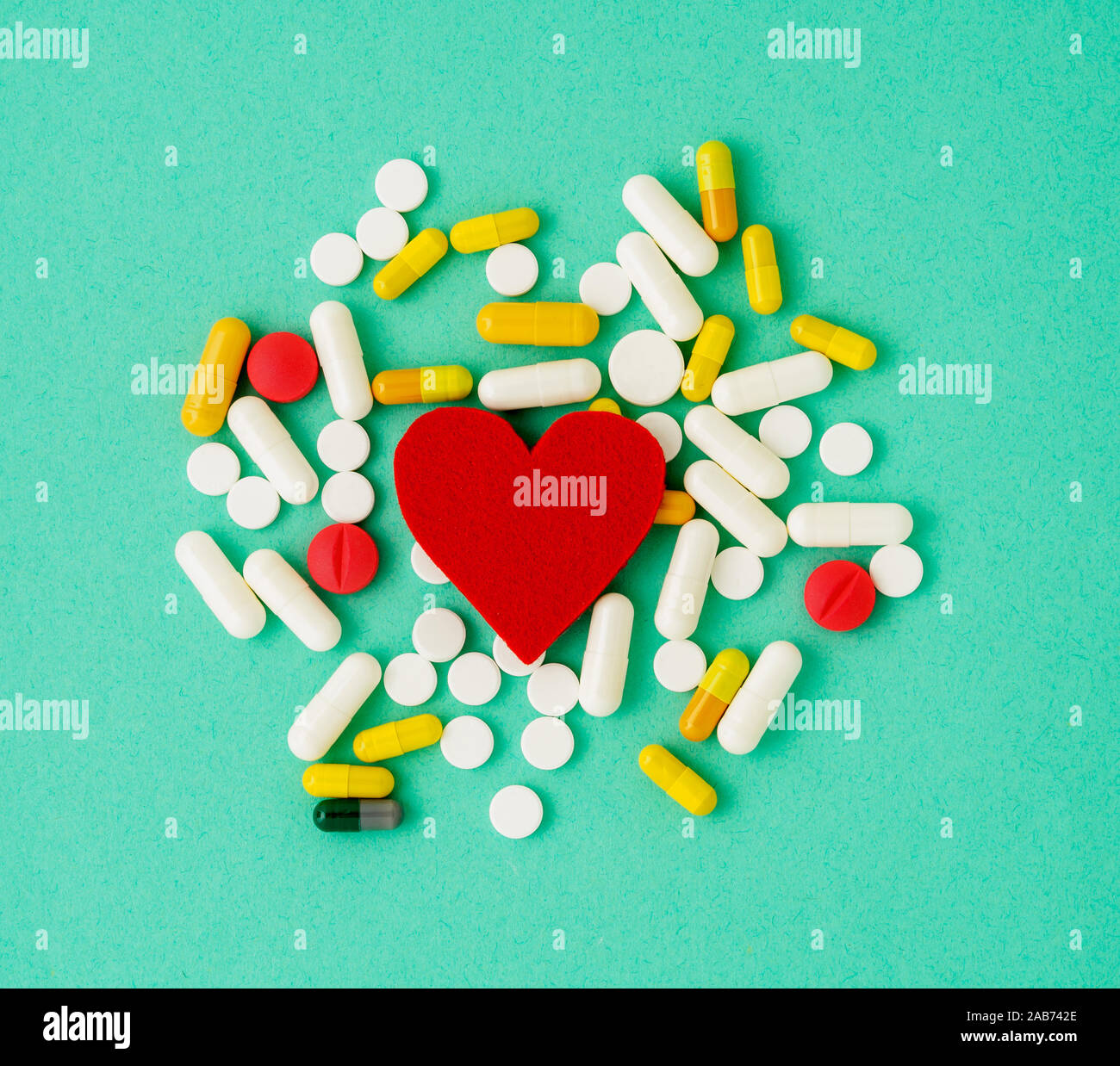 handful of pills and a red heart on a bright turquoise blue colour ...
