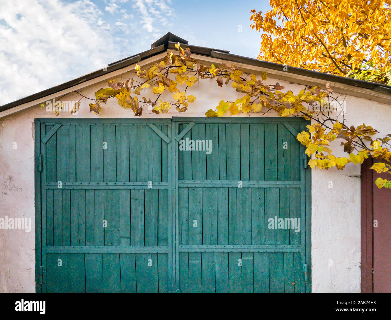 front view of an old garage with green wooden doors at sunny autumn day ...