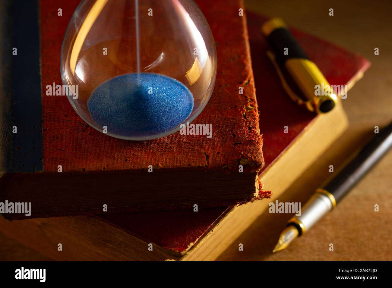 Hourglass on old book in morning light. Time of reading a book Stock ...