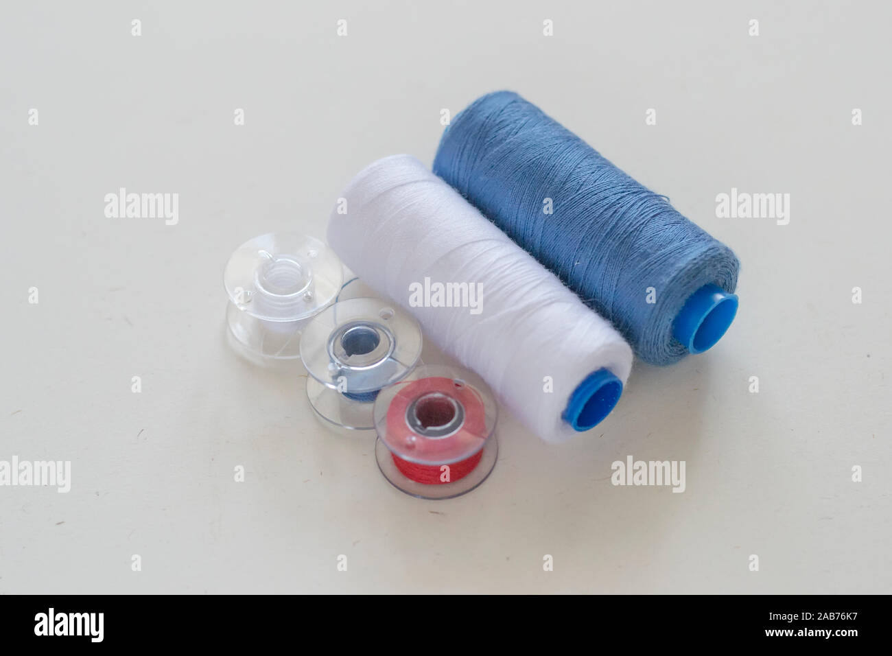 Colored bobbins and spools of thread for machine sewing on a light ...