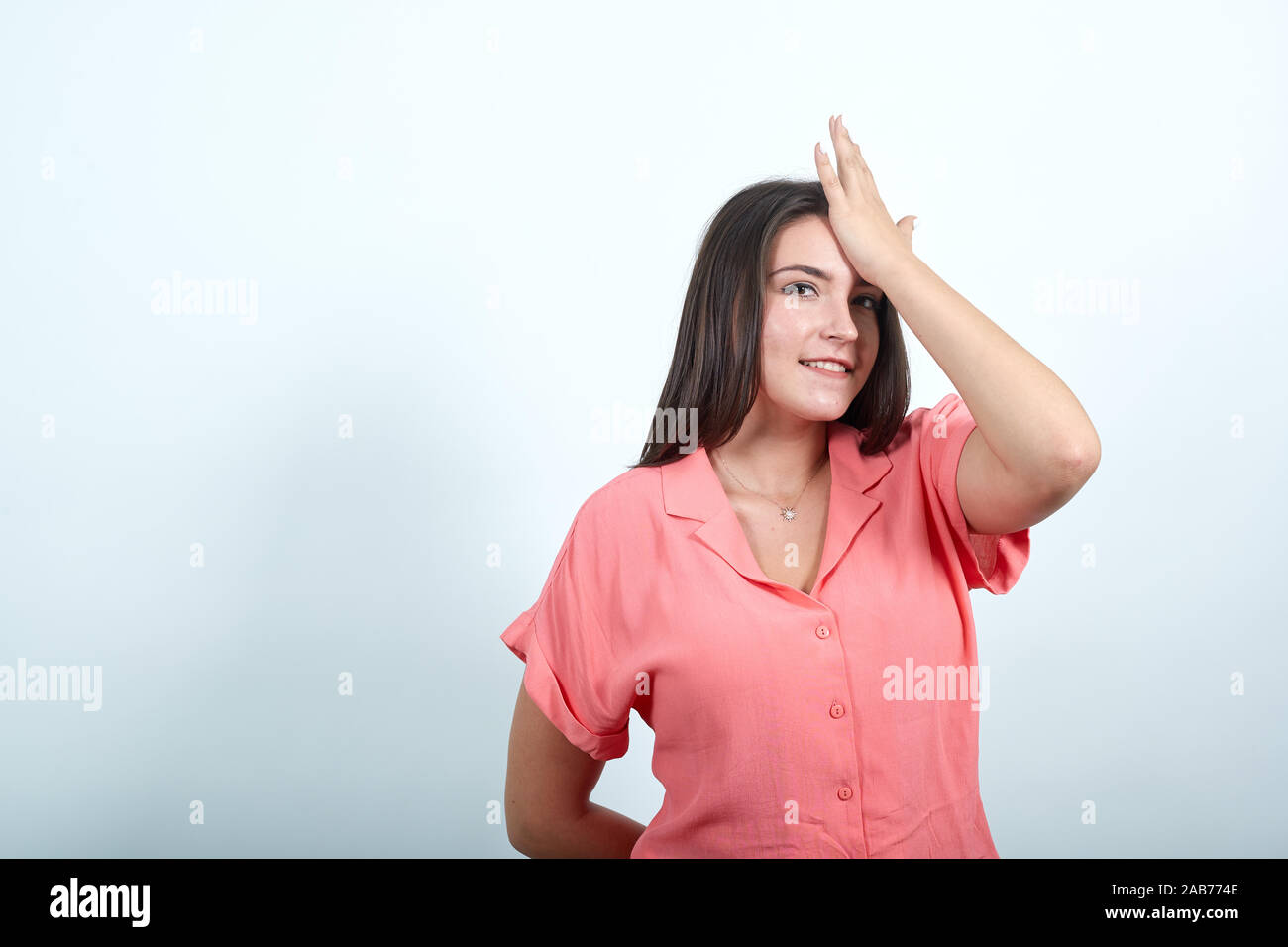 Attractive woman keeping hand on head, smiling, holding other hand ...