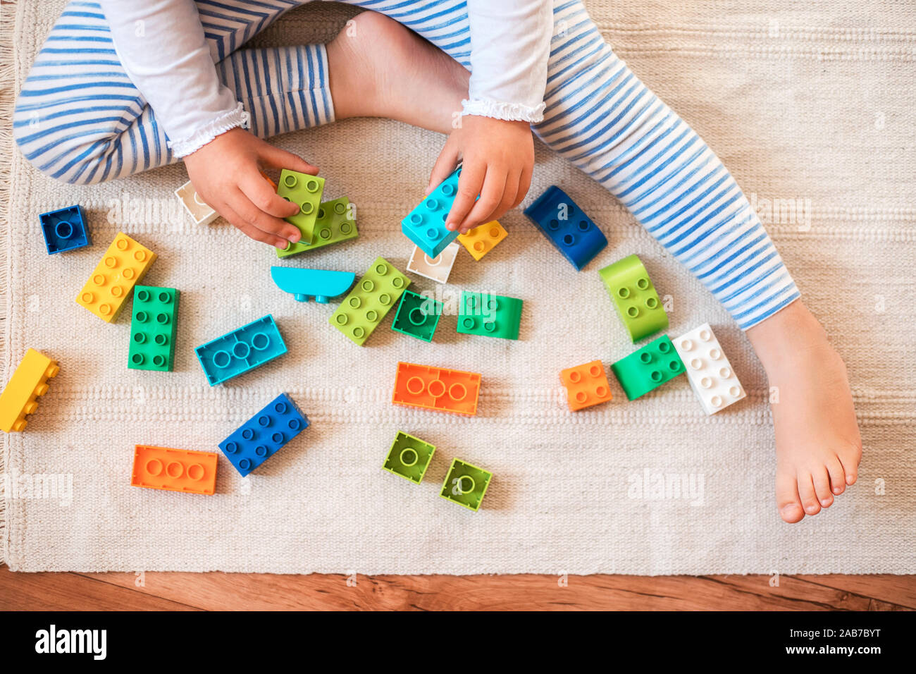 Little girl playing with her colorful blocks on the floor at home Stock ...