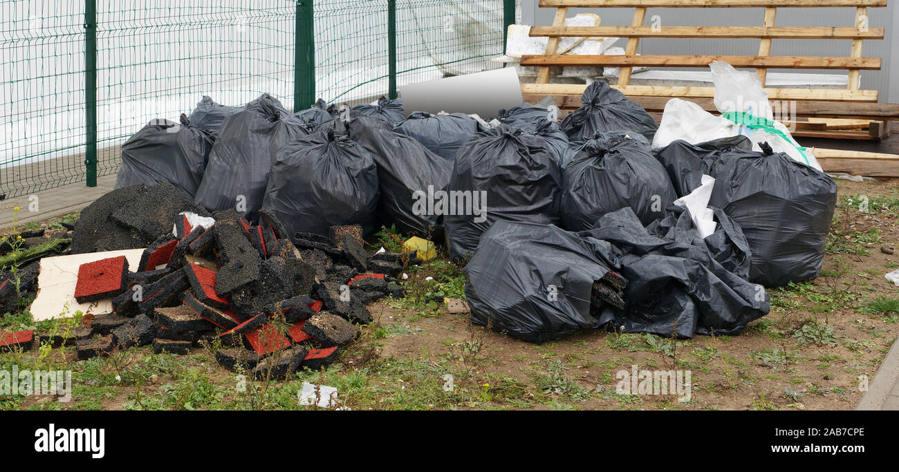Construction site debris in black plastic bags and broken wooden boards ...