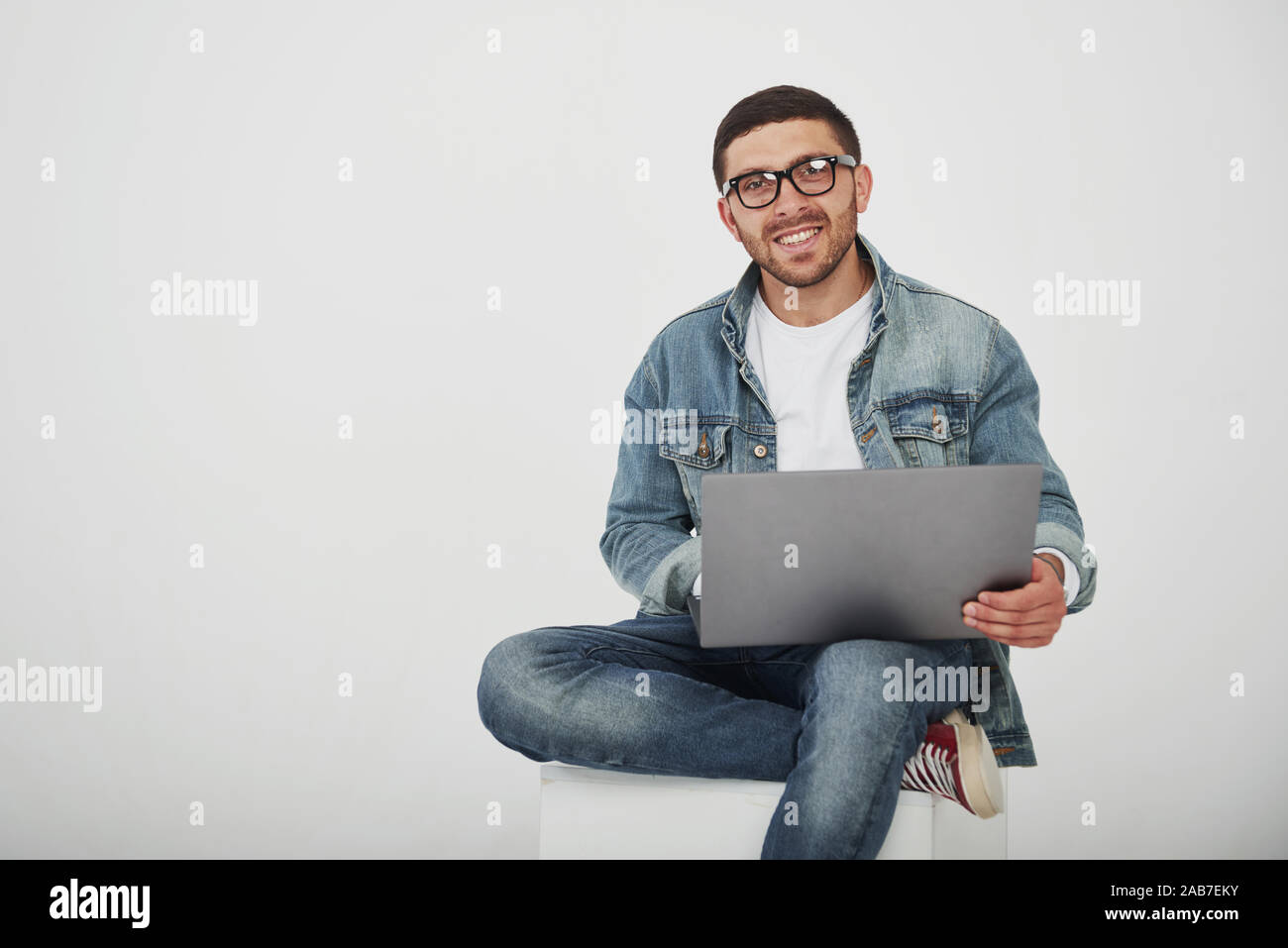 Handsome young man with laptop and check his timetable on white ...