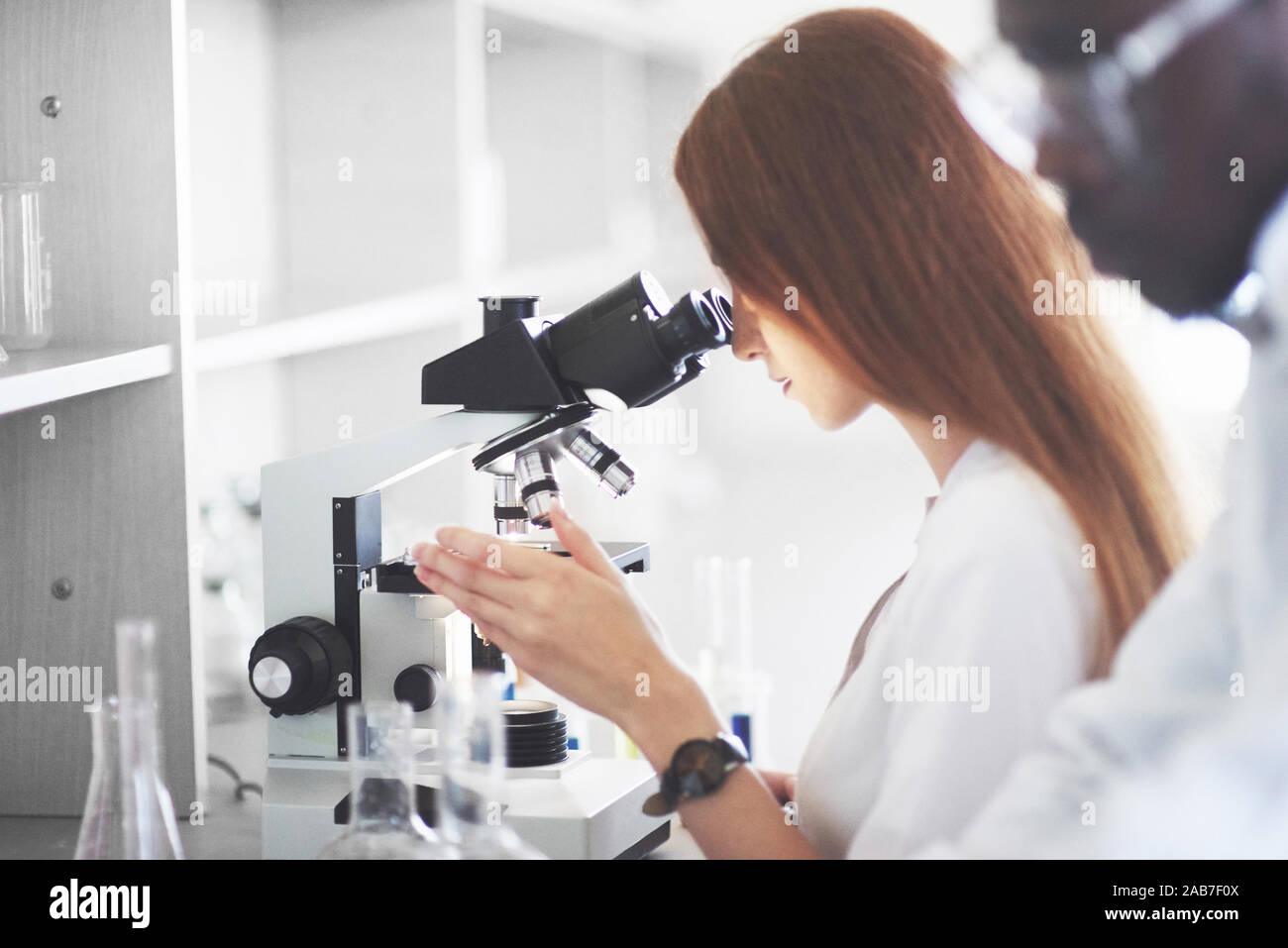 lab assistant with microscope laboratory glassware bulb with chemicals ...