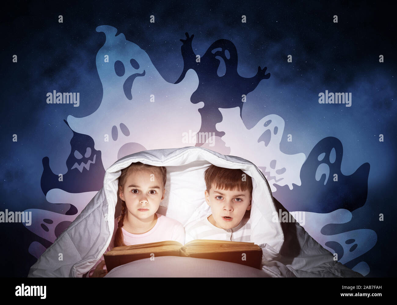 Scared girl and boy reading book in bed Stock Photo - Alamy