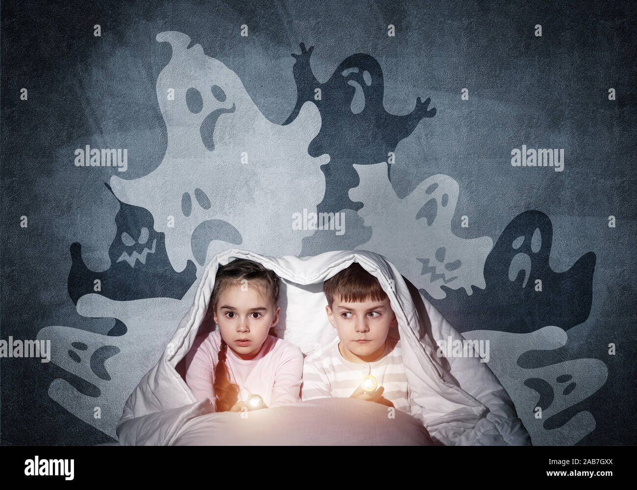 Scared girl and boy reading book in bed Stock Photo - Alamy