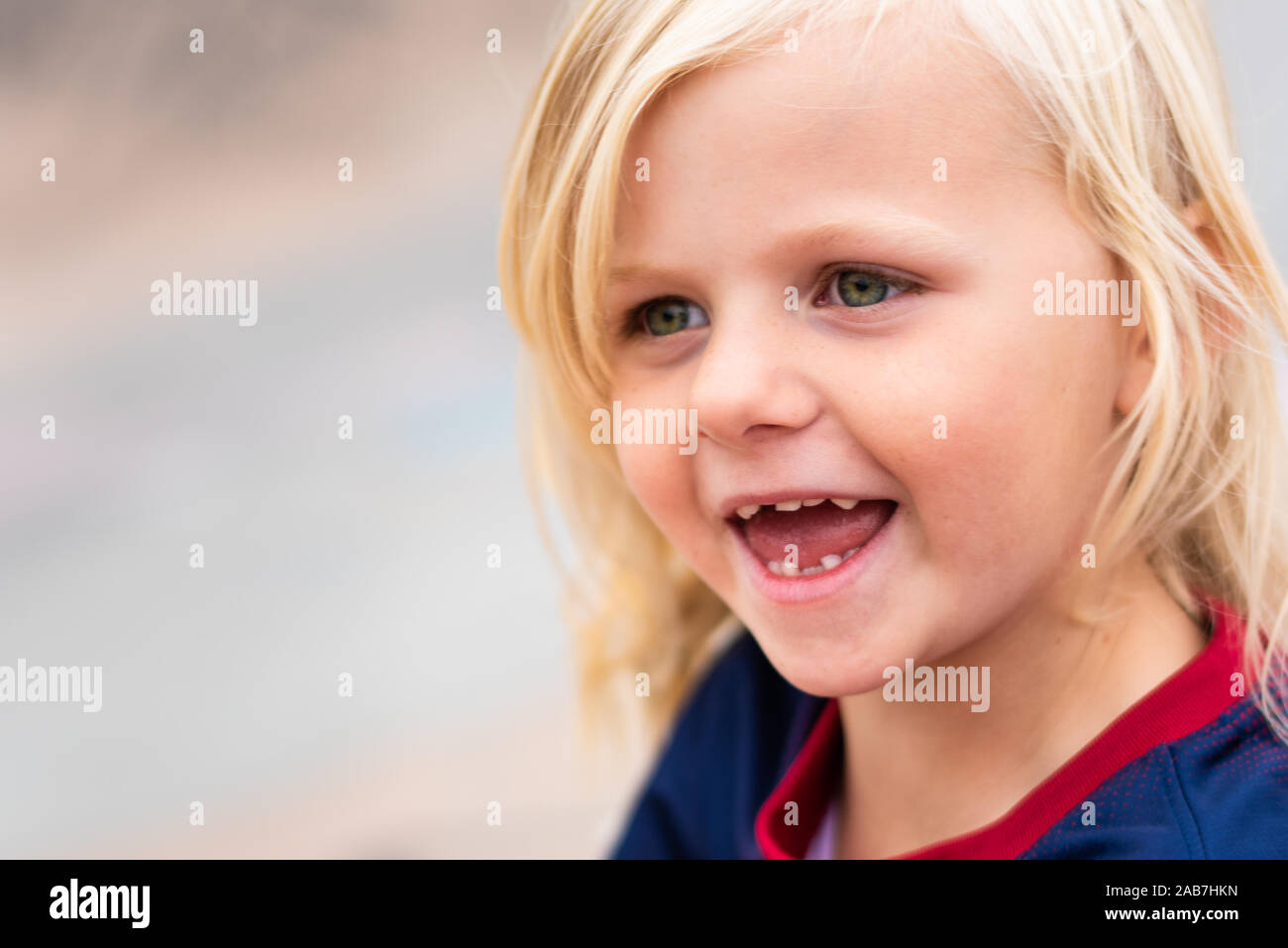 A cute, pretty little blonde haired girl wearing a football shirt being ...