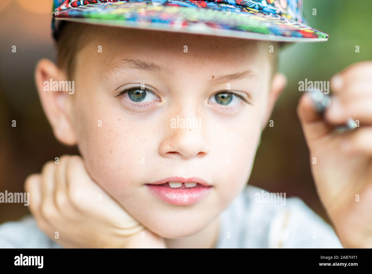 A handsome little boy with ADHD doing his homework, holding a pen while ...
