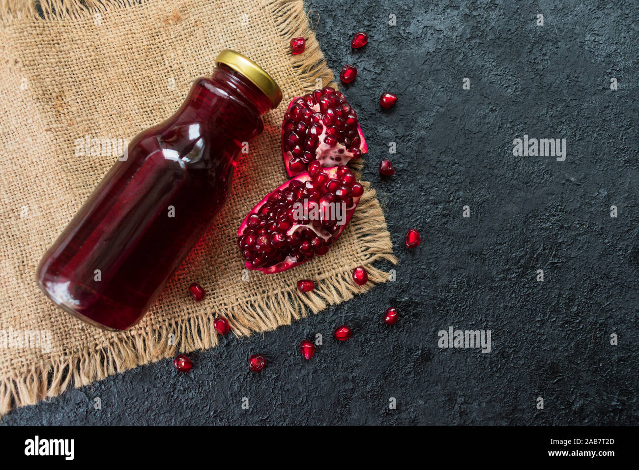Pomegranate juice in a bottle and pomegranate on a black background ...