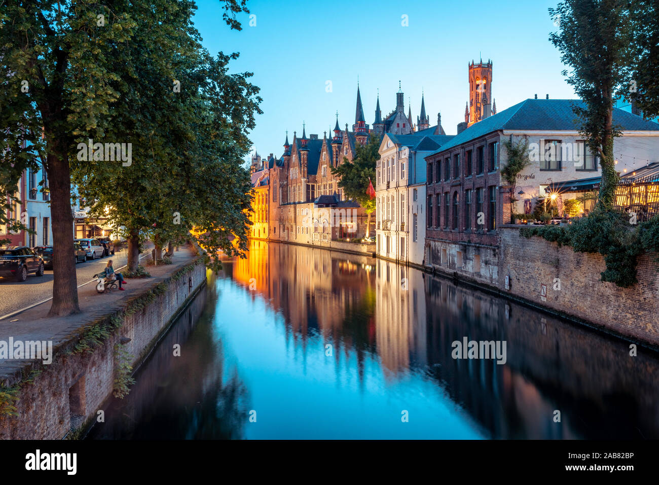 A tranquil canal scene in Bruges, with the spires of the Stadhuis (Town ...