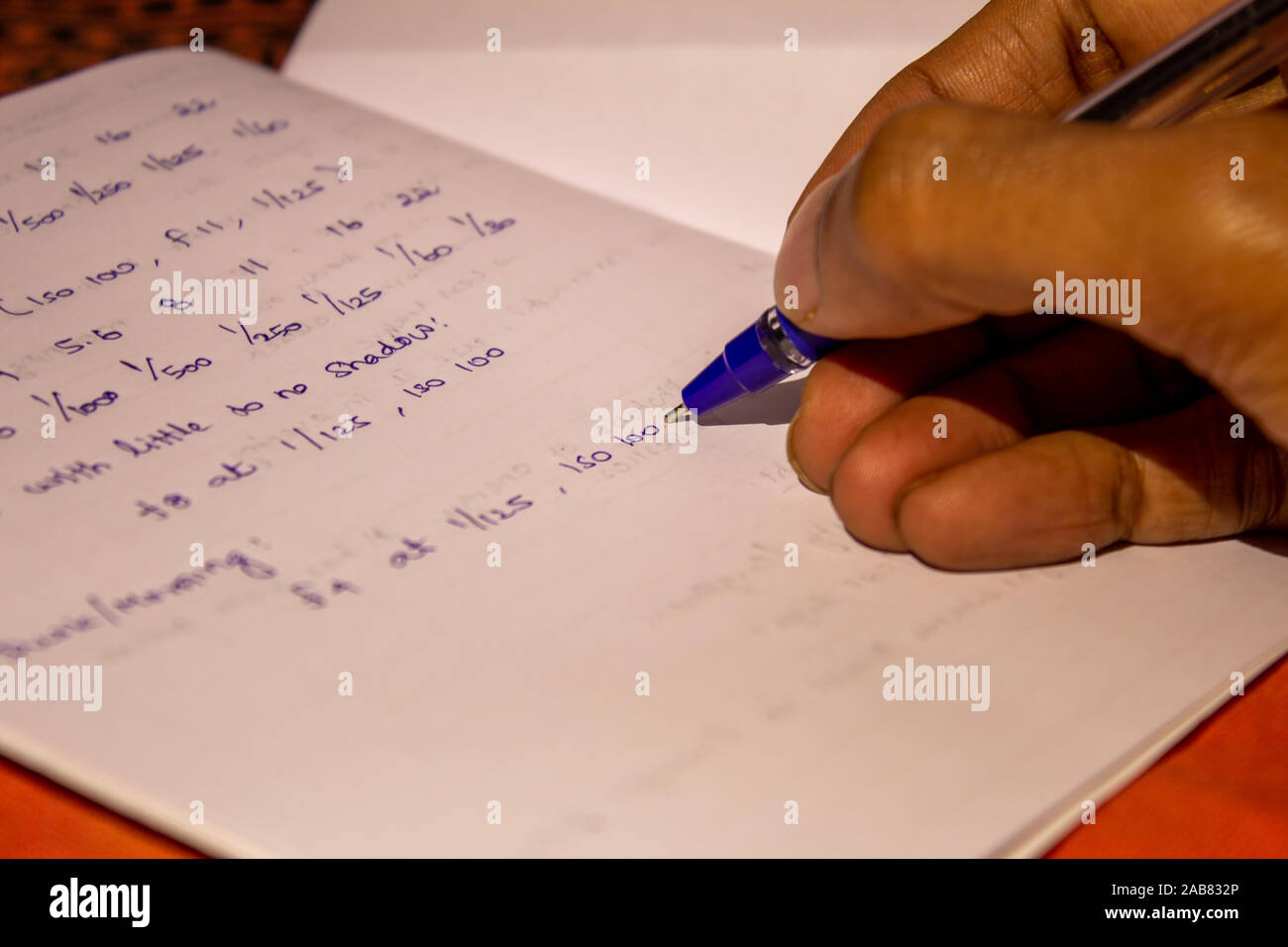 Person taking notes in a notebook. Making note of photographic tips in ...