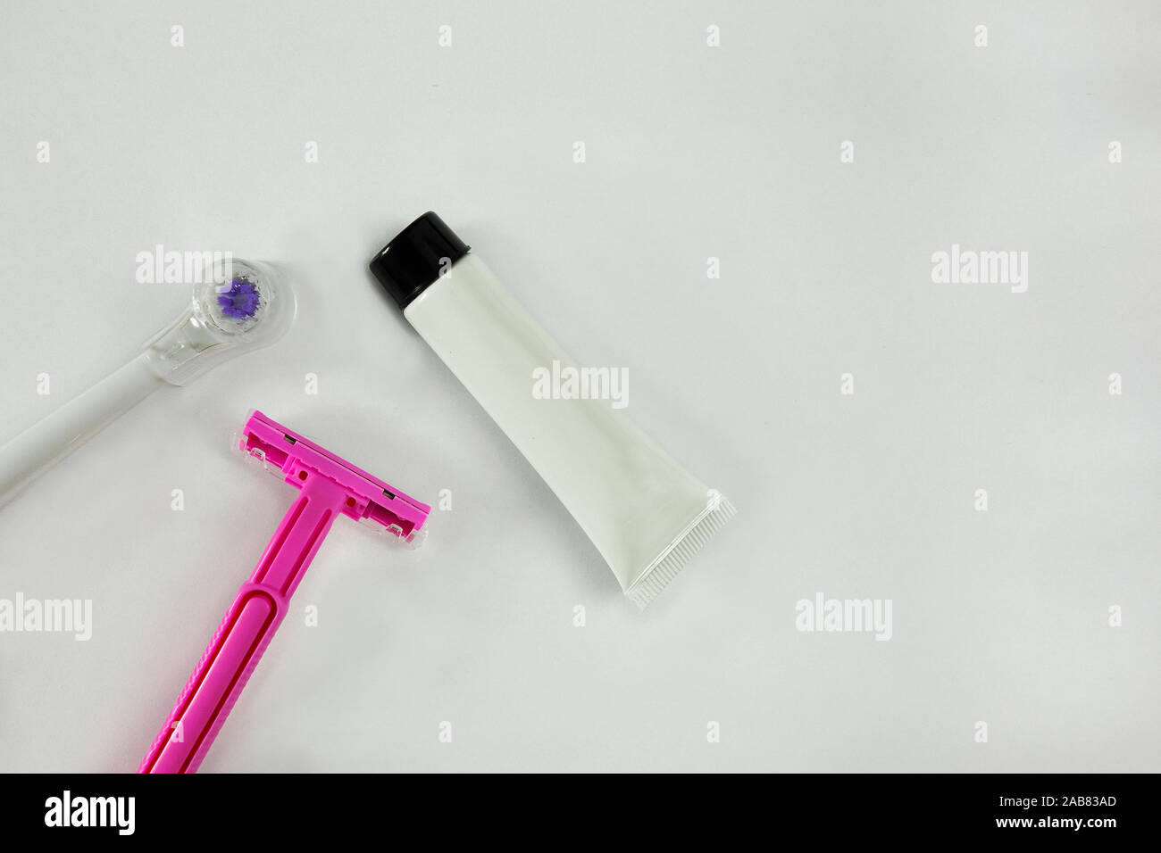 Pink shaving stick, removable toothbrush head and white tube with cream ...