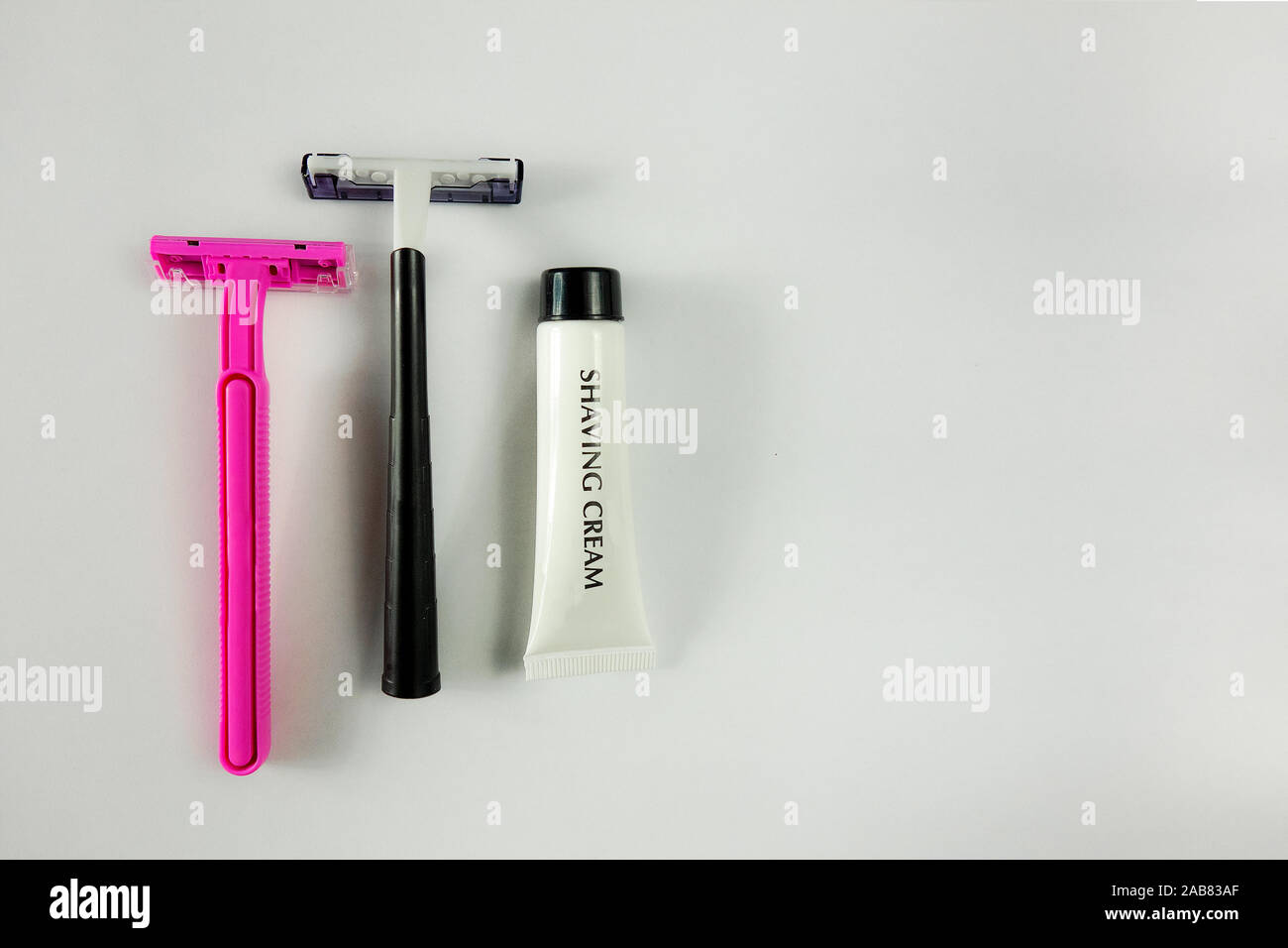 Two shaving sticks and white tube with shaving cream on light ...