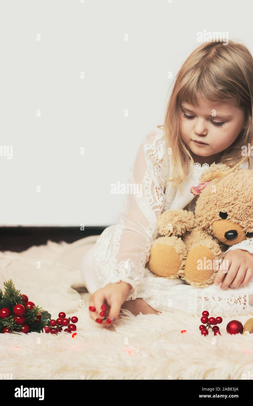 Little girl sitting on the carpet, with her teddy bear, playing with ...