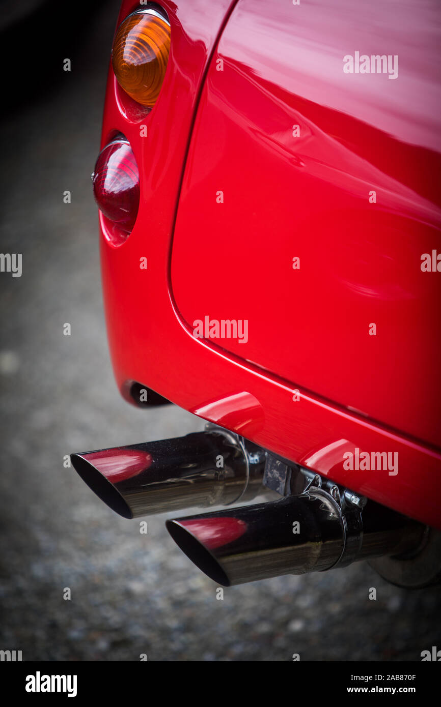 Close up vertical image of the red tail light and exhaust pipes of a ...
