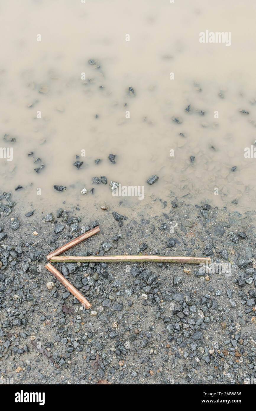 Survival skills concept. Signal arrow on gravel 'proceed this way ...