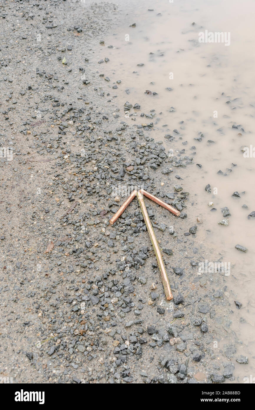 Survival skills concept. Signal arrow on gravel 'proceed this way ...