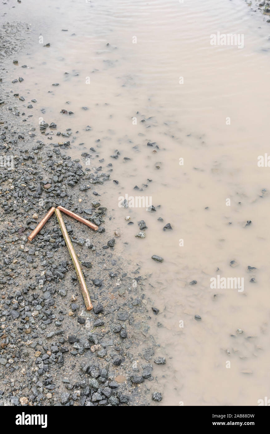 Survival skills concept. Signal arrow on gravel 'proceed this way ...