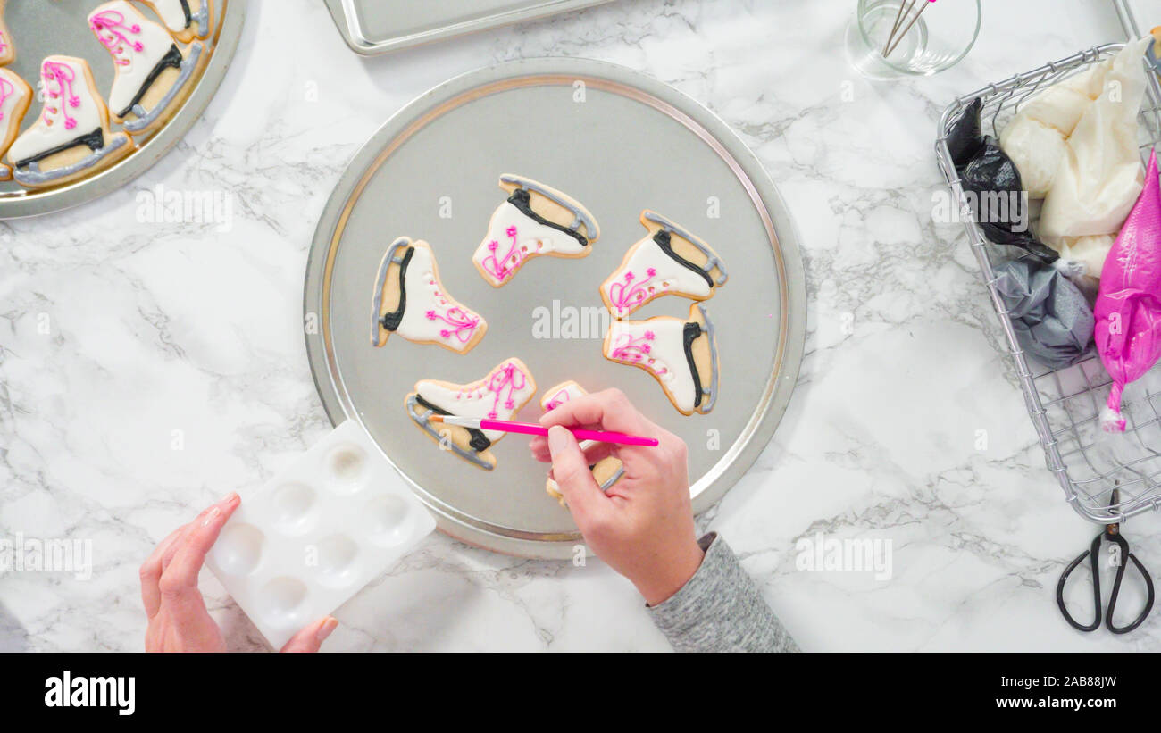 Flat lay. Brushing edible glitter on iced figure skate sugar cookies ...