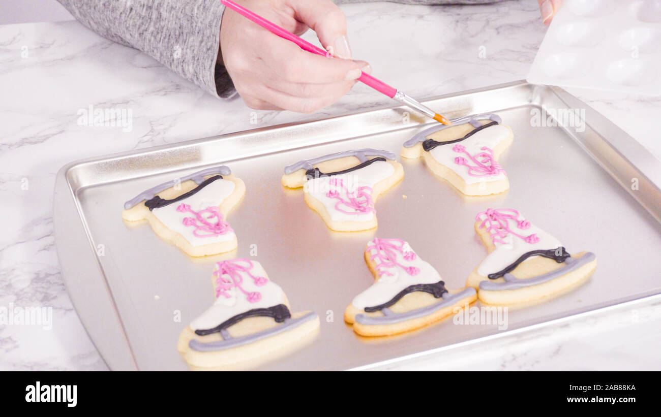 Brushing edible glitter on iced figure skate sugar cookies Stock Photo ...