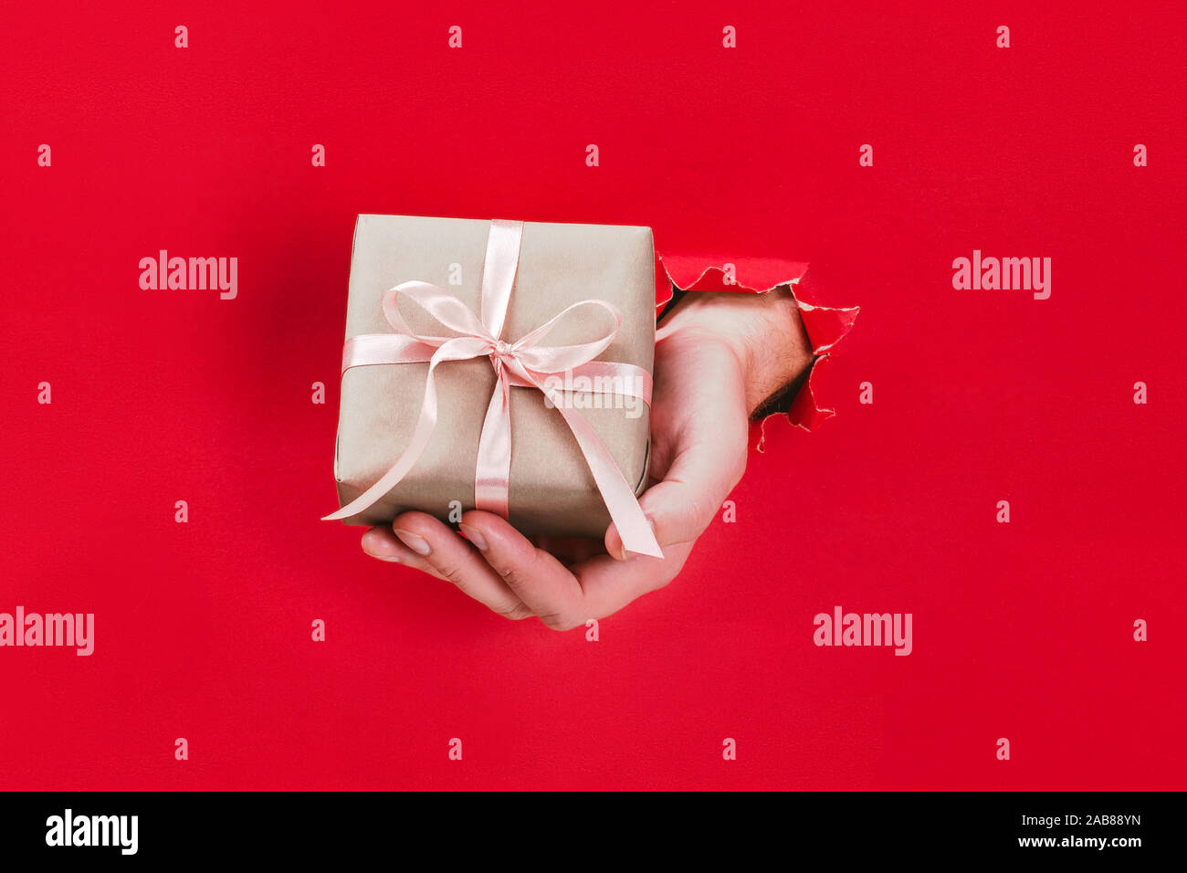 Male hand holding gift box wrapped in craft paper with pink ribbon ...