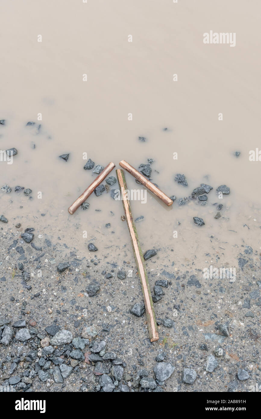 Survival skills concept. Signal arrow on gravel 'proceed this way ...