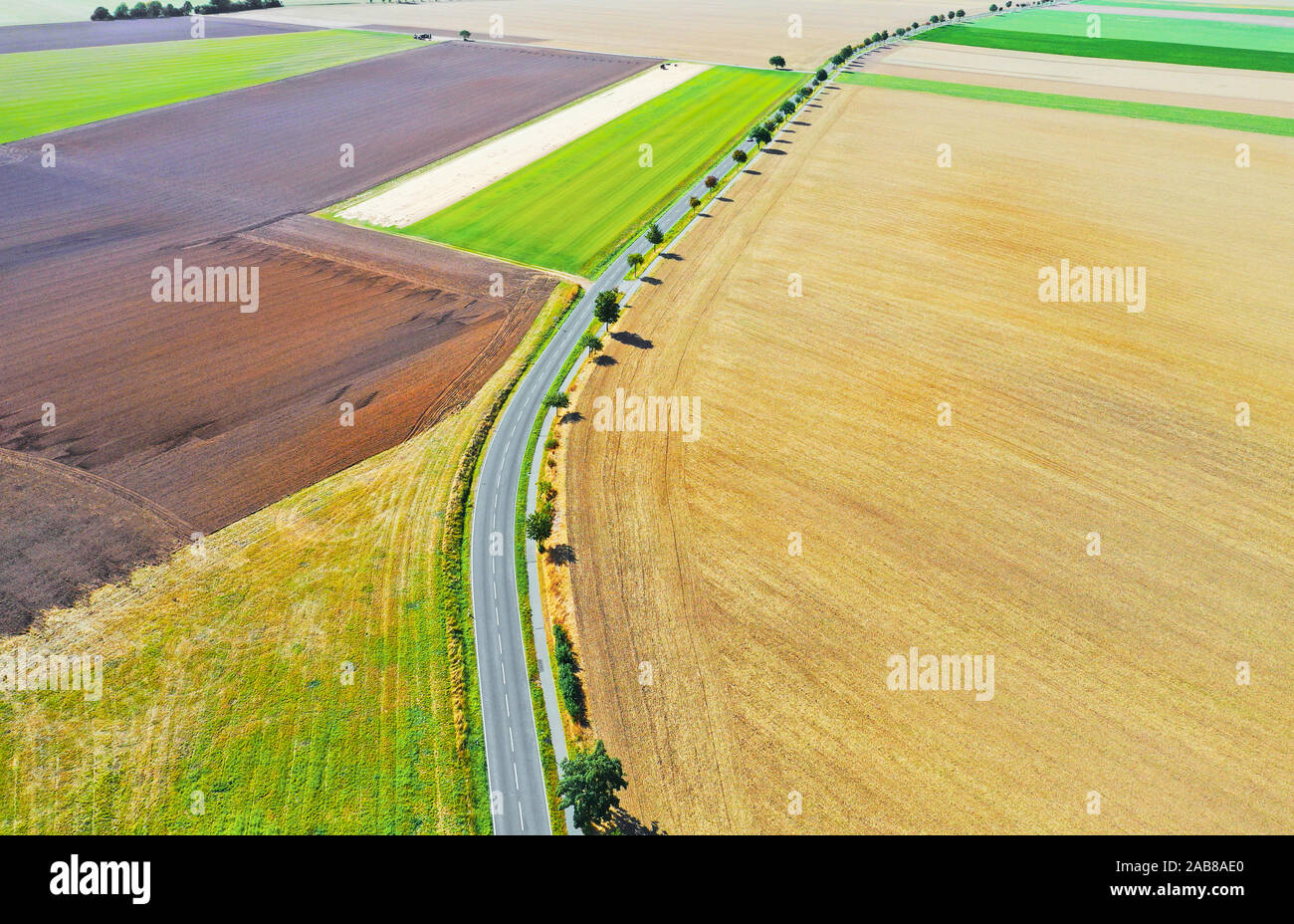 Aerial view of a grey asphalted narrow country road, which runs ...