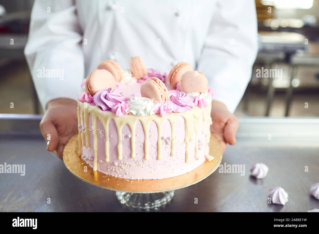 Confectioner's hands hold a pink cake in a candy store. Pink cake on ...