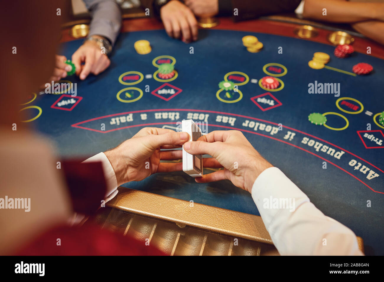The croupier holds poker cards in his hands at a table in a casino ...