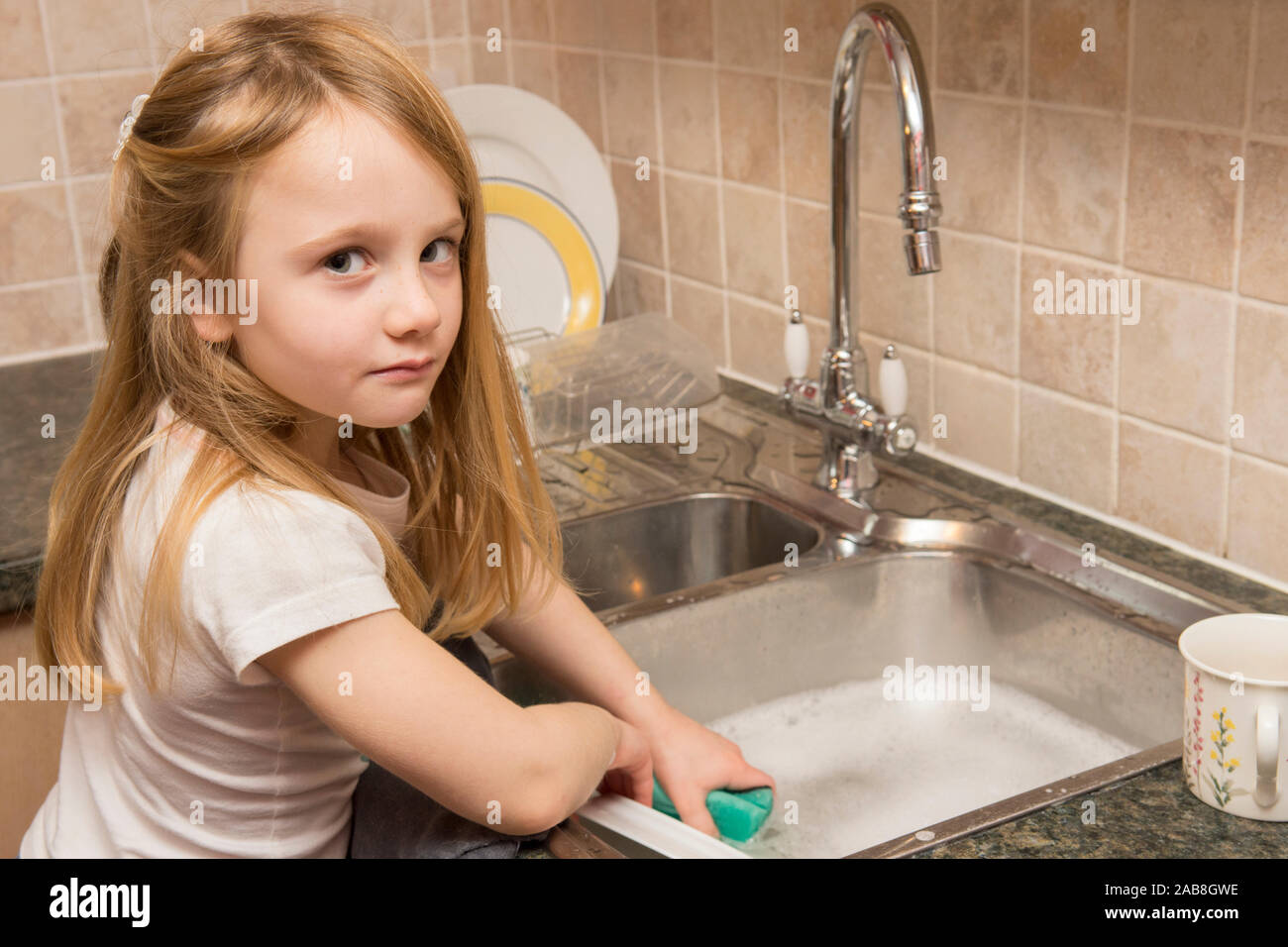 young child washing up at kitchen sink, home chores, unhappy Stock ...
