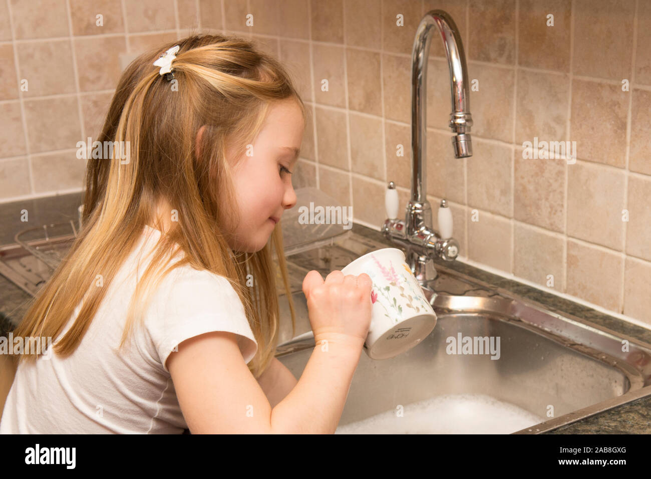 young child washing up at kitchen sink, home chores, smiling, happy ...