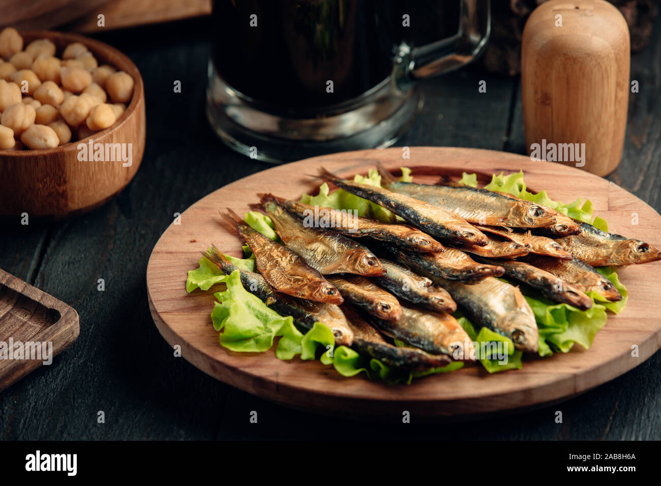 dried smoked sprat layered on lettuce leaves served on round wood ...