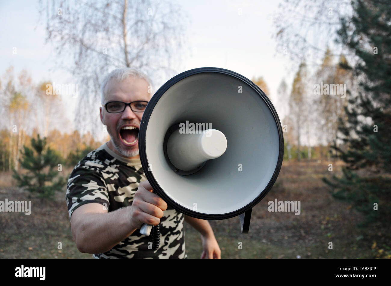 Closeup portrait of a young man screaming into a megaphone. Shout ...