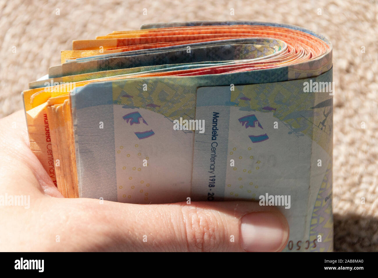 A close up view of one and two hundred rand notes folded over in a ...