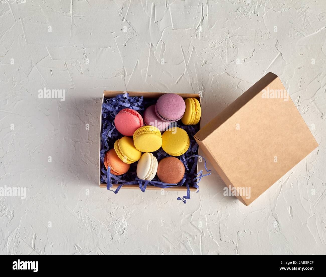 open cardboard box with a baked dessert multi-colored round macarons ...