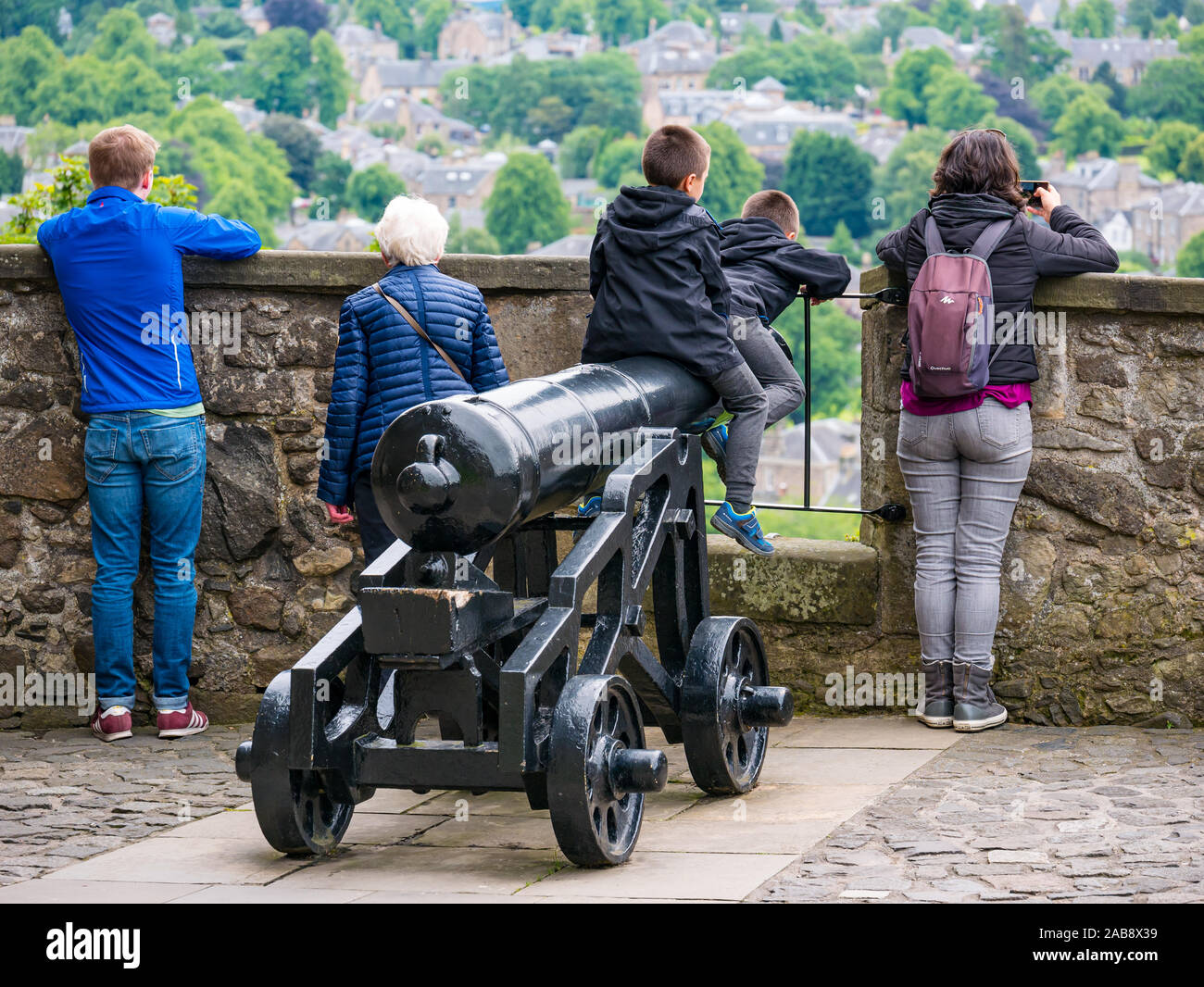 Twin boys playing on old cannon gun and people looking out from castle ...