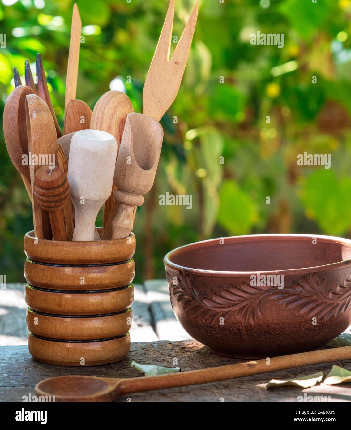 empty clay plate and various wooden kitchen objects in a container on a ...