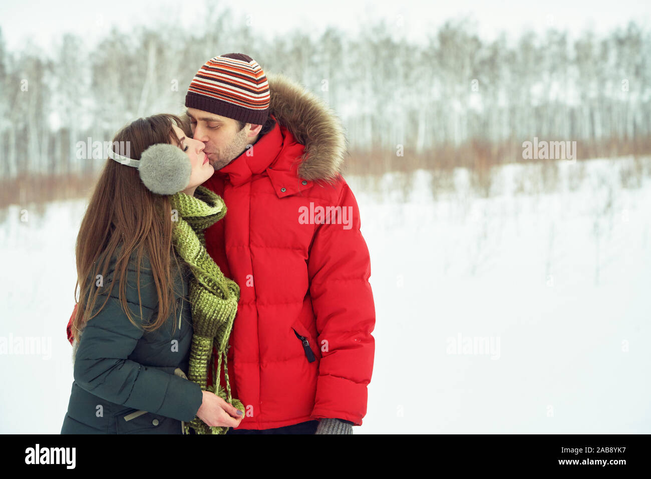 Young happy kissing couple in love in the winter outdoors Stock Photo ...
