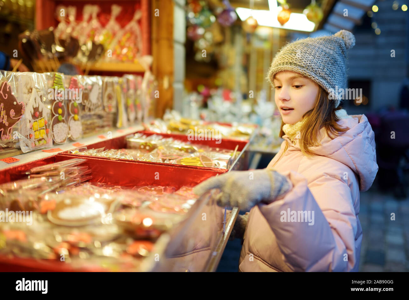Cute young girl choosing sweets on traditional Christmas market in Riga ...