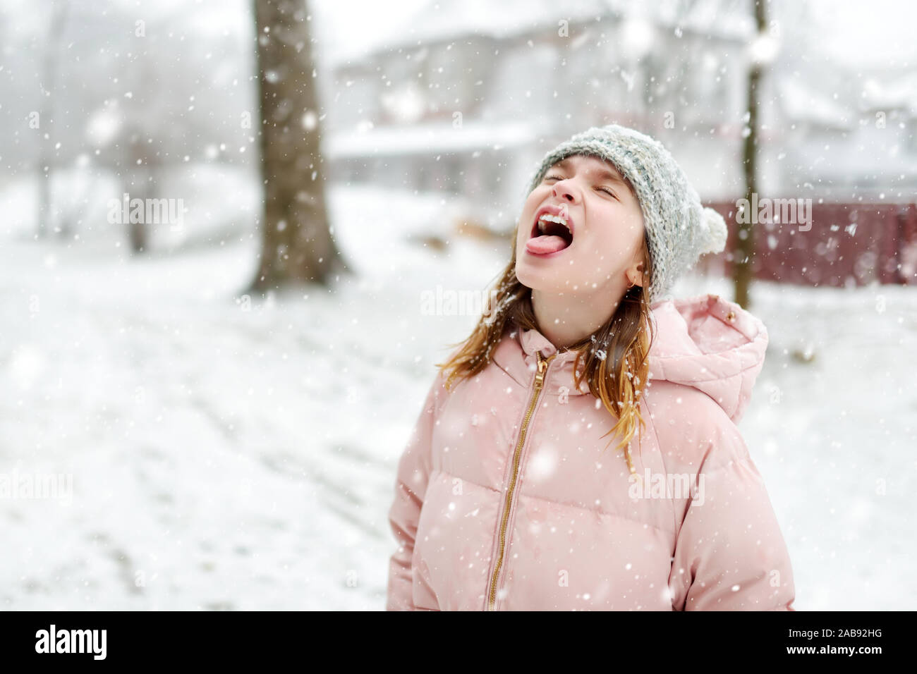 Adorable young girl catching snowflakes with her tongue in beautiful ...