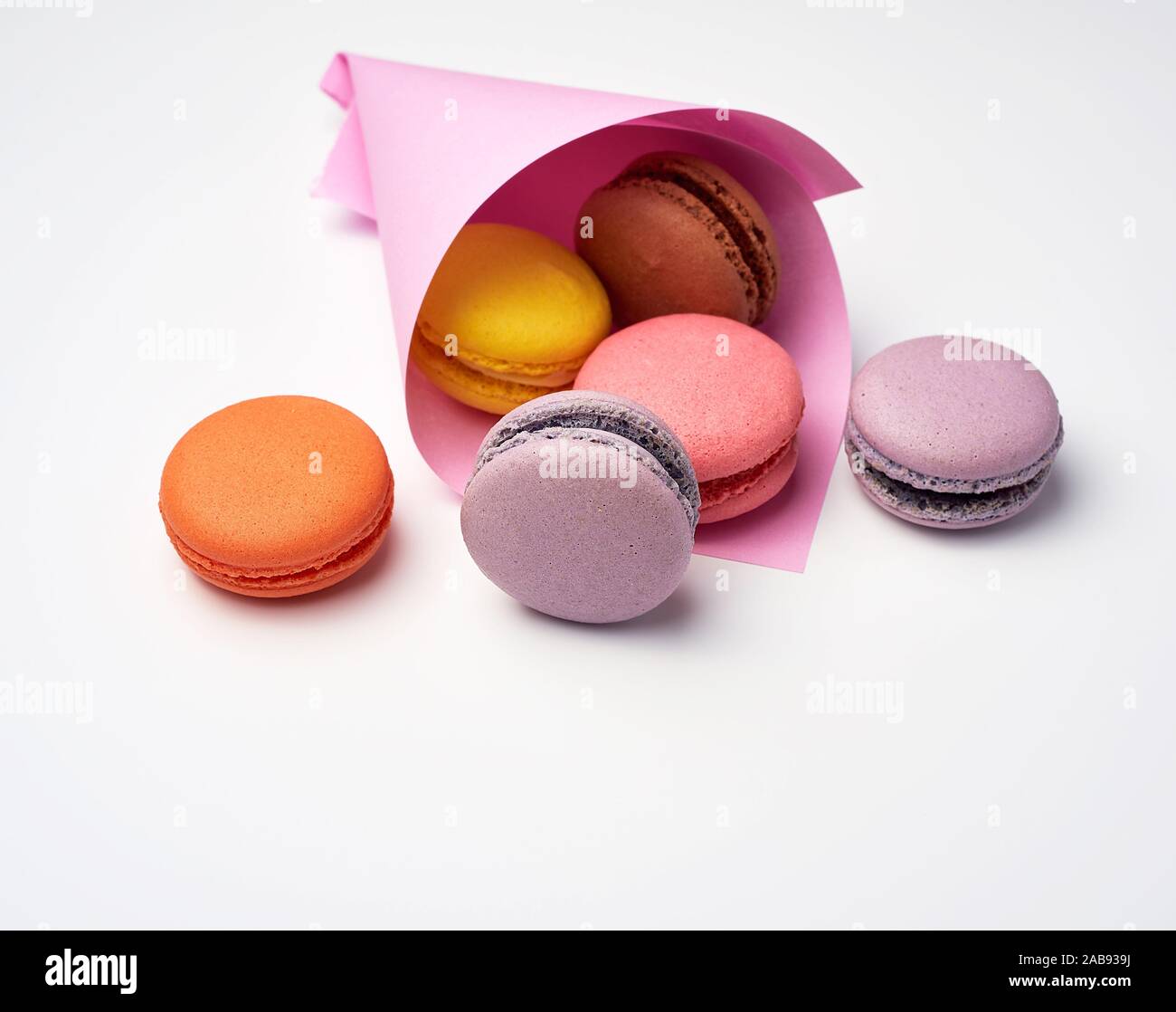 baked macarons in a pink paper bag on a white background, close up ...