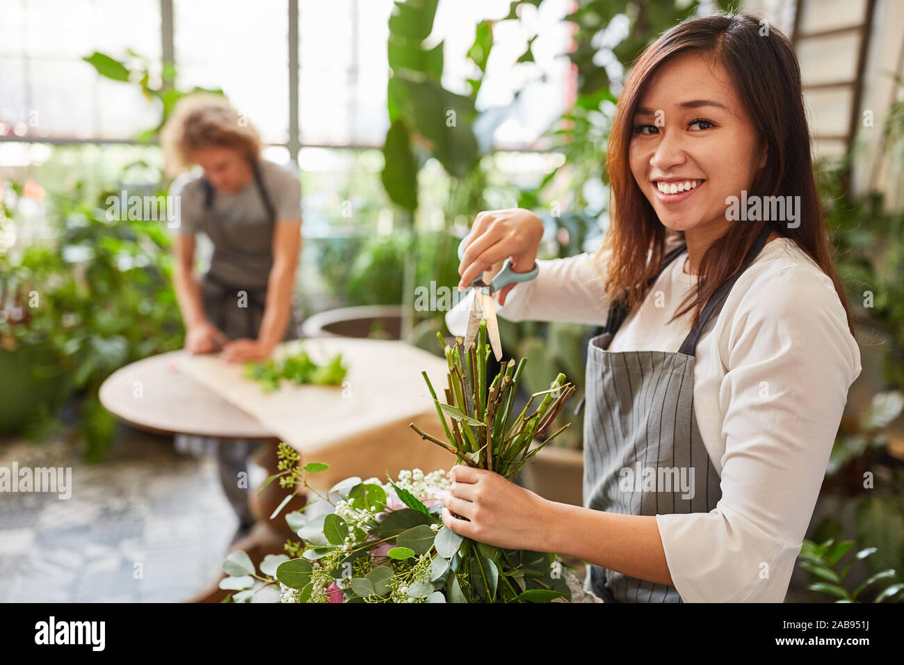 Cut florist in training with flower scissors while holding flowers ...