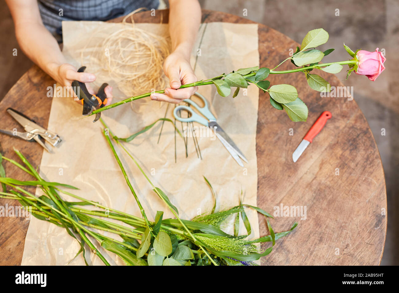 Florist cuts with flower scissors a rose while tying the bouquet Stock ...
