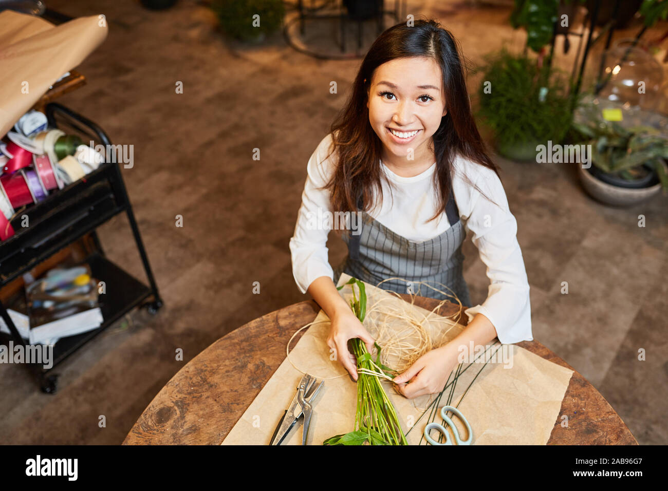 Young florist in training while tying flowers in flower shop Stock ...