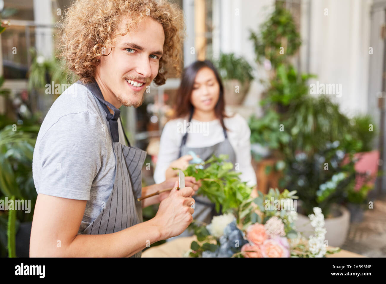 Young man as florist in training learns to tie bouquet Stock Photo - Alamy