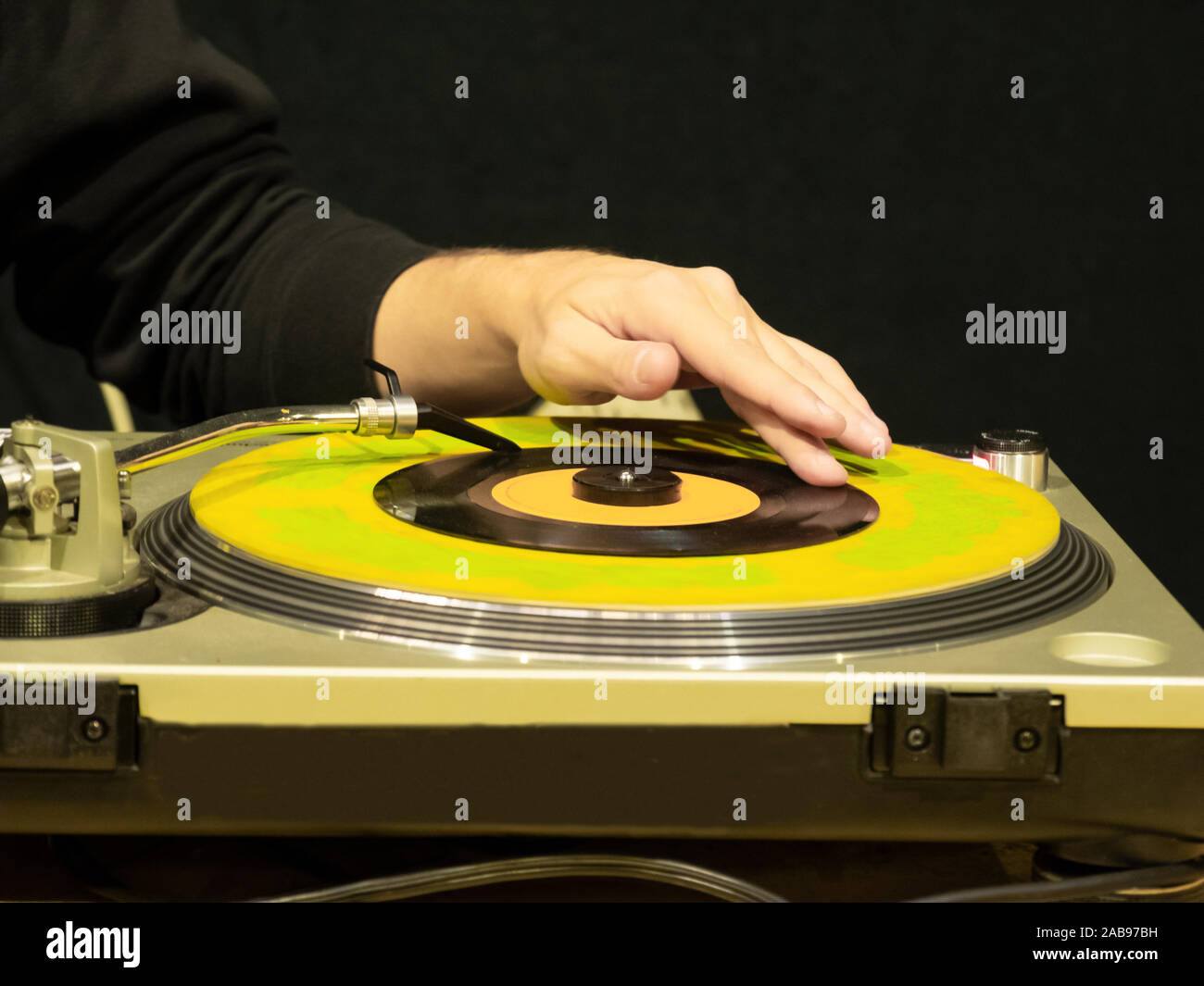 a disc jockey while transmitting a track on a vinyl record in a disco ...