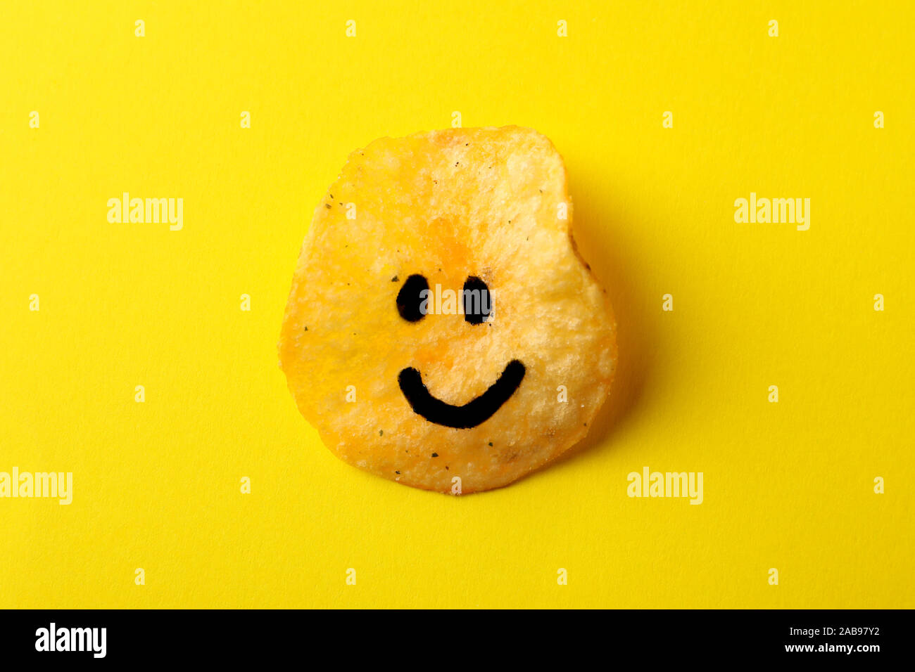 Potato chips with smile on yellow background, space for text. Top view ...