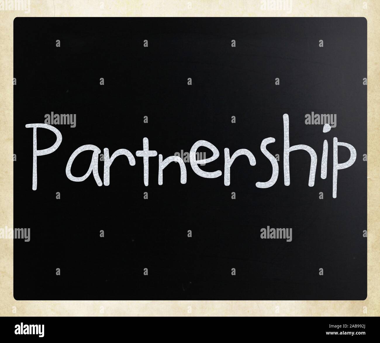 The word 'Partnership' handwritten with white chalk on a blackboard ...